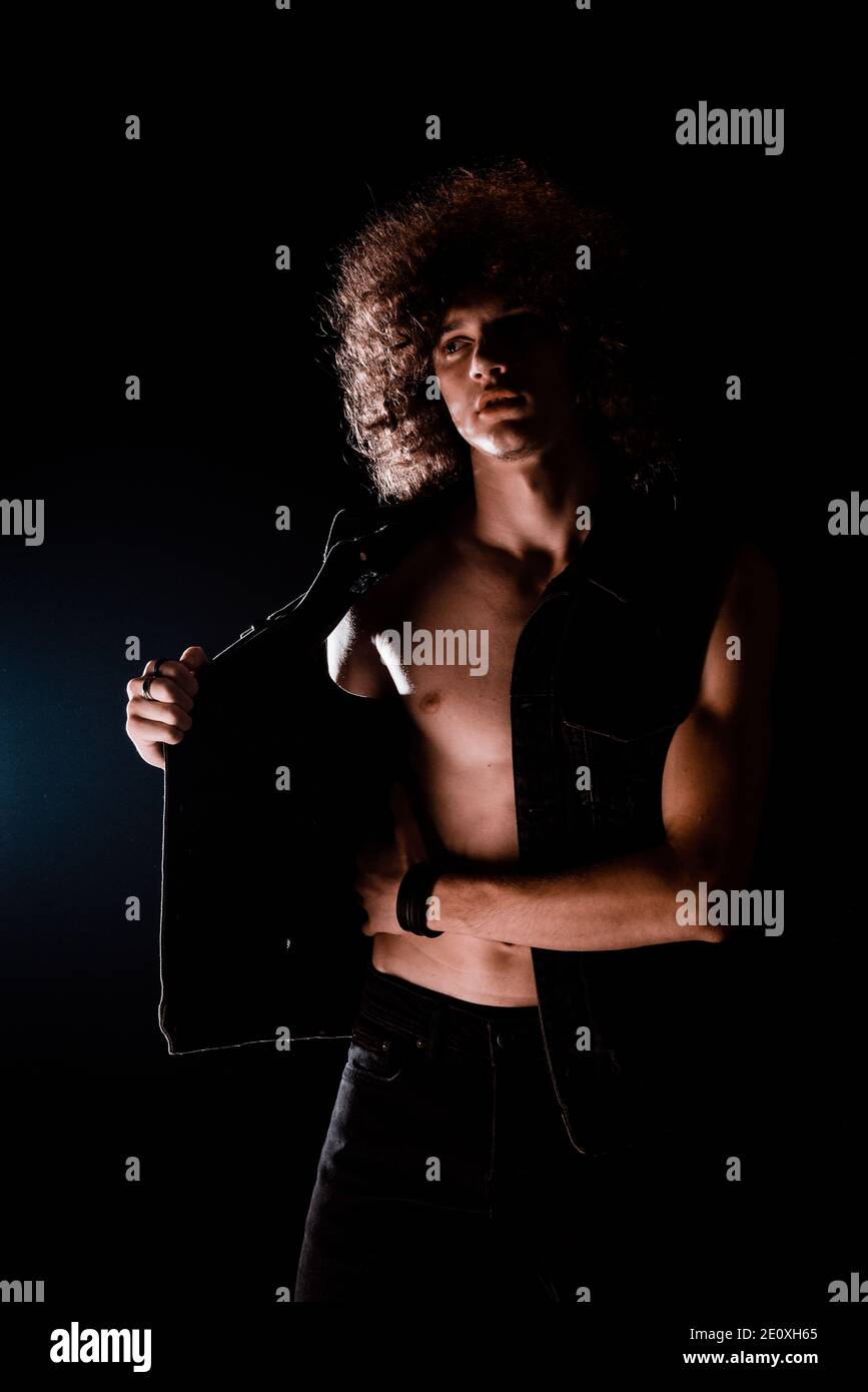 Skinny rock guy wearing unbuttoned black jeans vest isolated on black ...