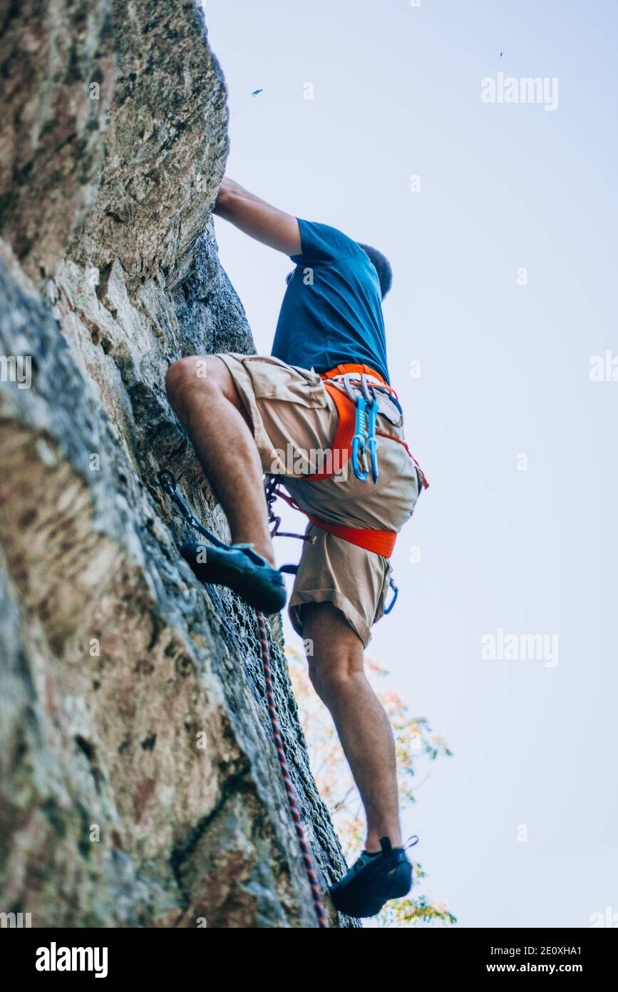 Man climbing a rock short before reaching the summit Stock Photo - Alamy
