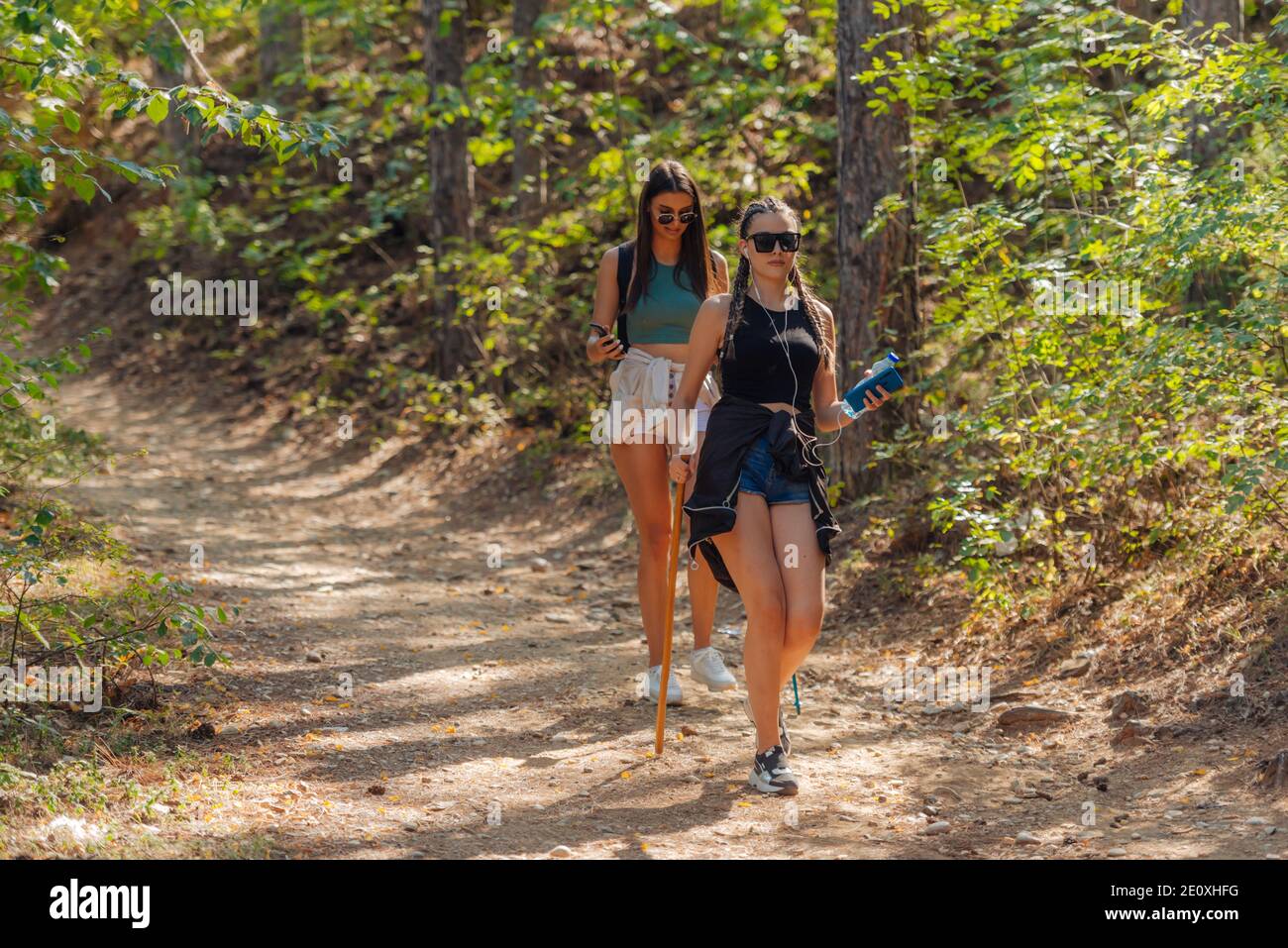 Sisters hiking through beautiful woods while wearing a backpack and ...