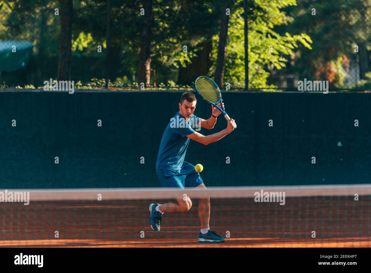 Professional equipped male tennis player beating hard the tennis ball ...