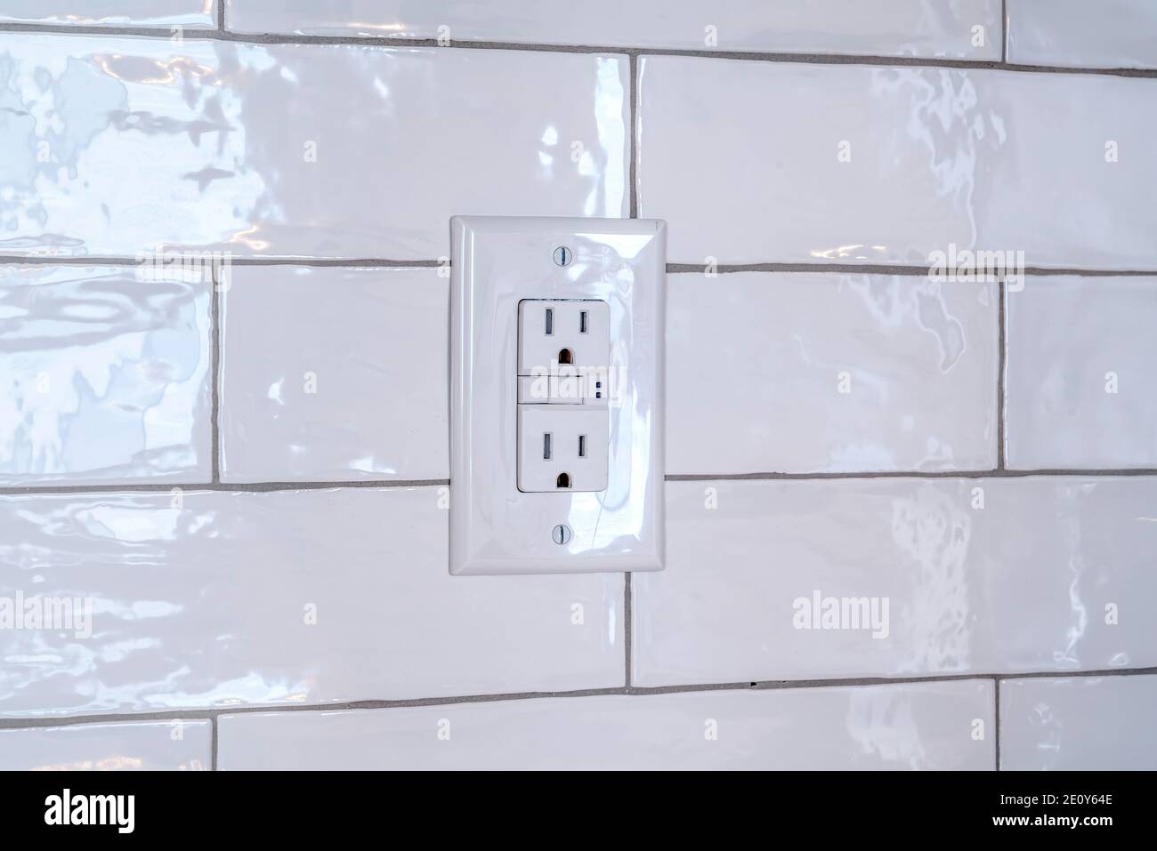 Three slot grounded receptacle for electric appliances on tiled wall of ...