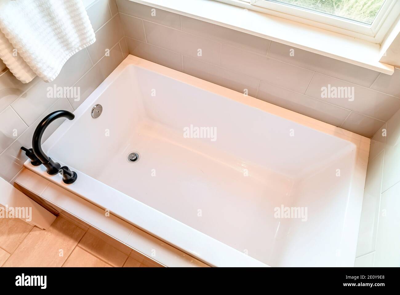 Built in rectangular bathtub with black gooseneck faucet inside home ...