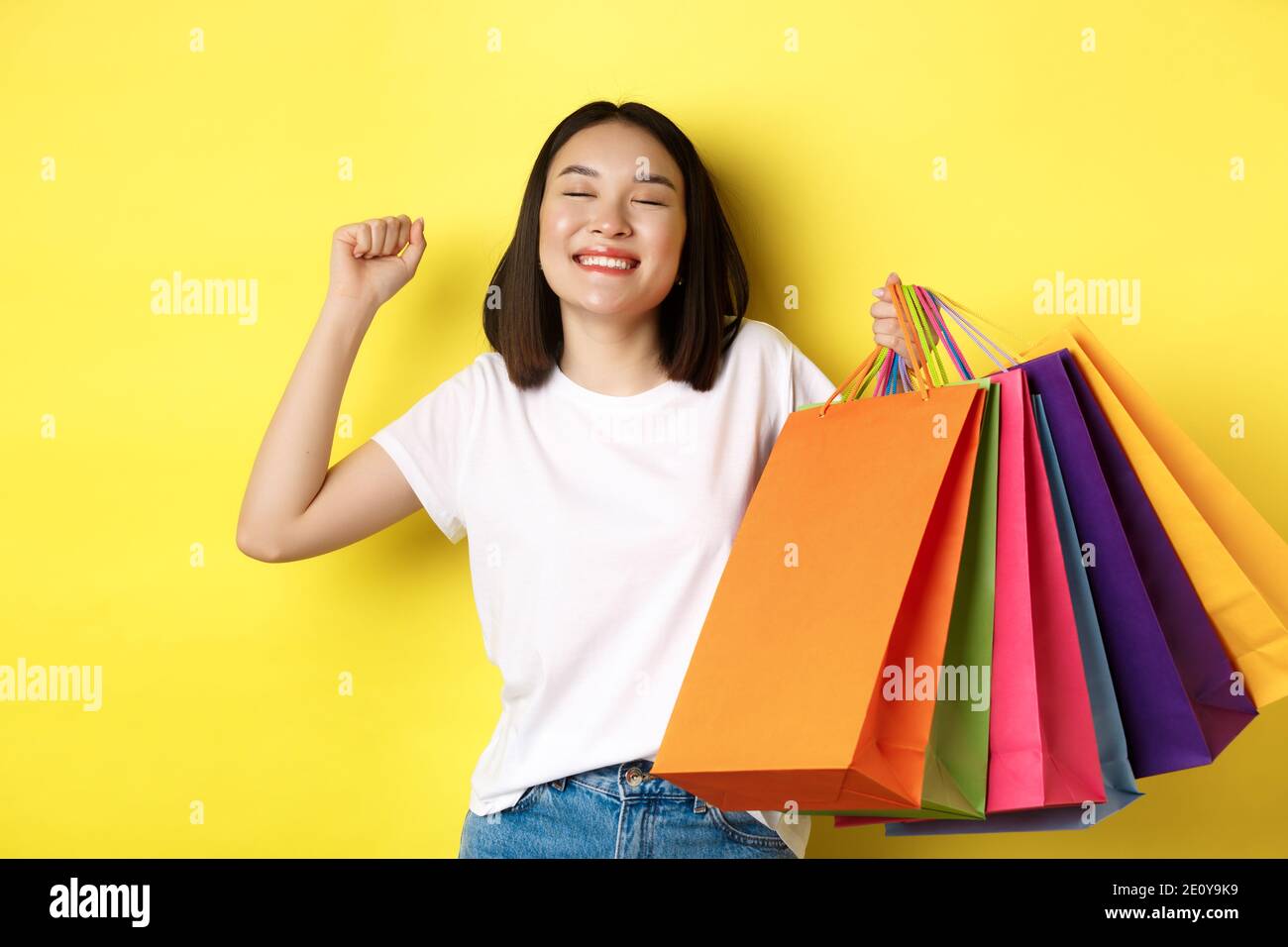 Happy asian woman feeling satisfied after shopping on sale, holding ...