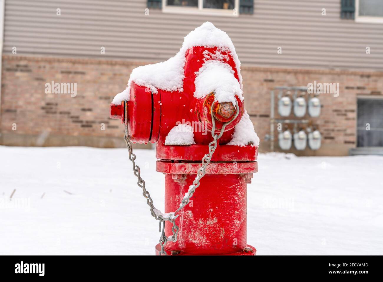 Close up of a bright red fire hydrant against snow and building in ...