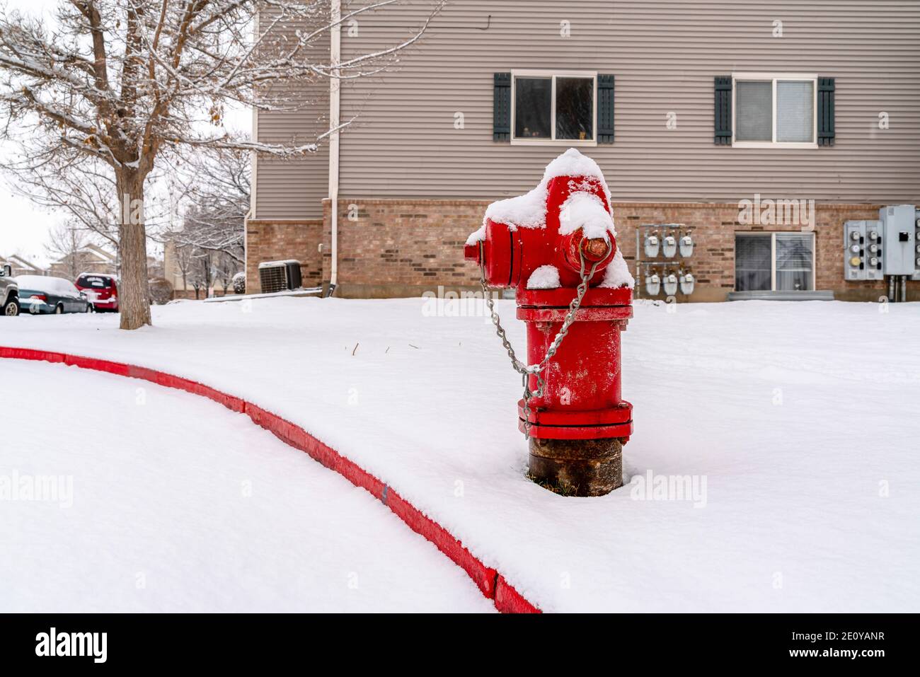 Bright red fire hydrant on the roadside of community covered with snow ...