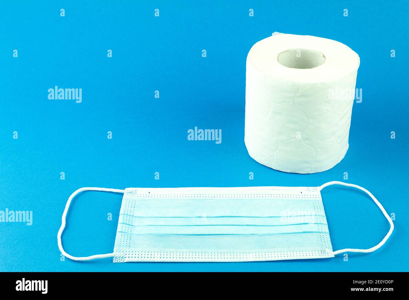 Rolls of toilet paper and a medical mask on a blue background. White ...