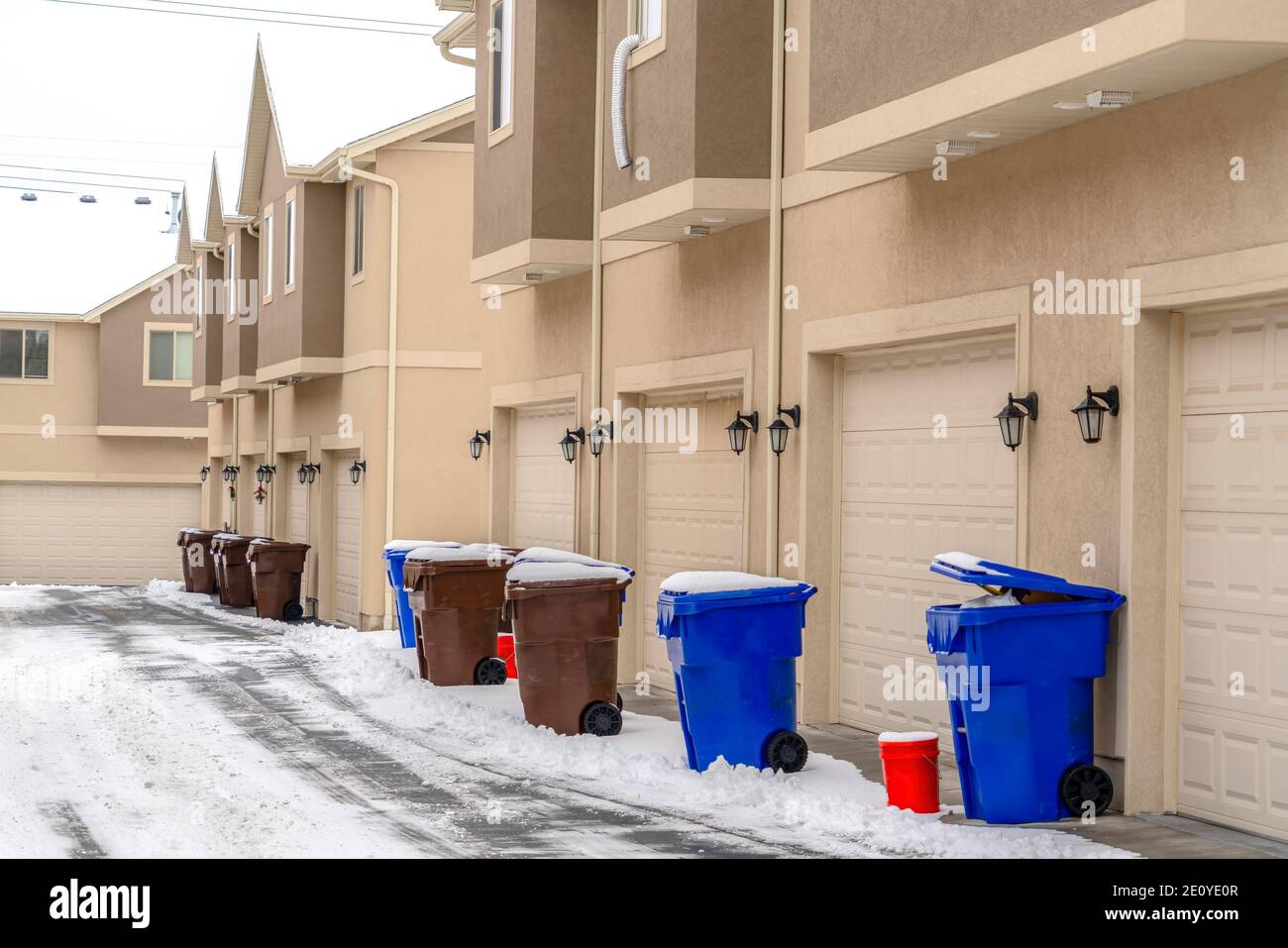 Exterior of apartments with garbage cans in front of the white garage ...