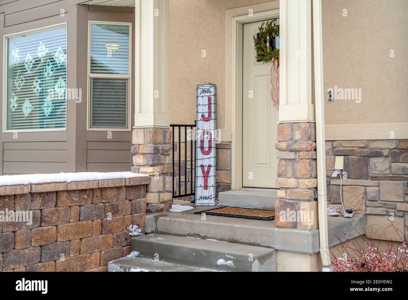 Joy sign board and wreath at home facade with bay window during holiday ...