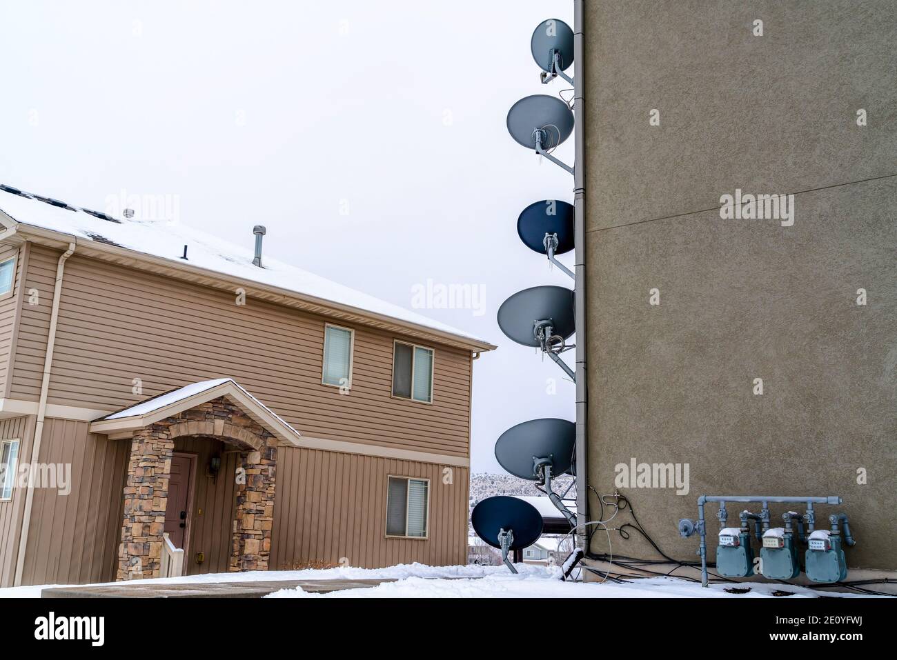 Parabolic satellite dishes and electricity meters on exterior wall of ...