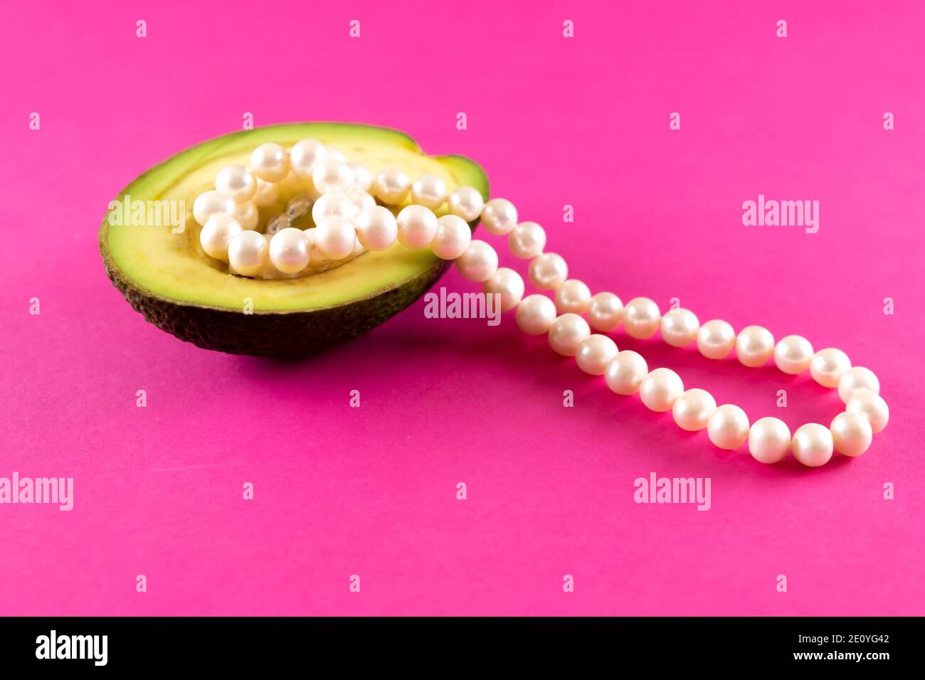 half avocado with pearls on pink background Trendy food design Stock ...