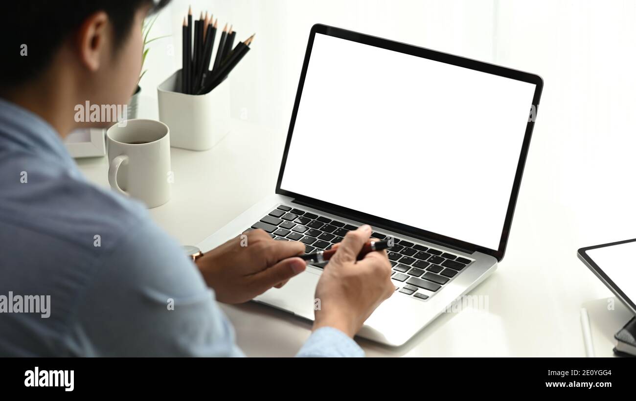 A young man working on computer laptop on his workspace.Blank screen ...