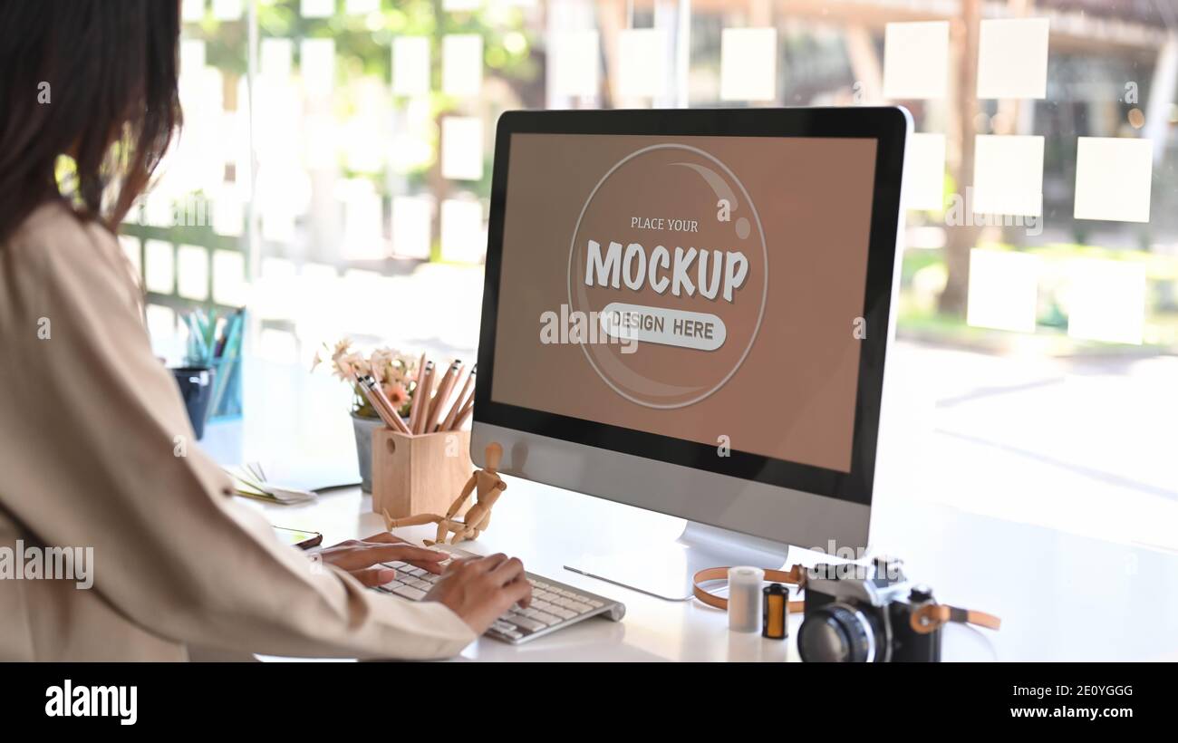 Side view of female designer working on computer in office. Blank ...