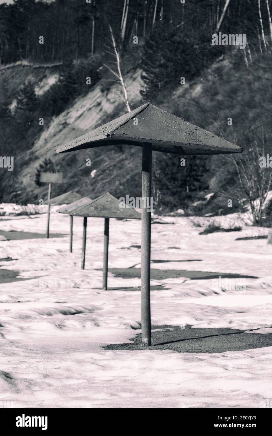 Abandoned rusty beach umbrellas on a beach covered with snow. In old ...