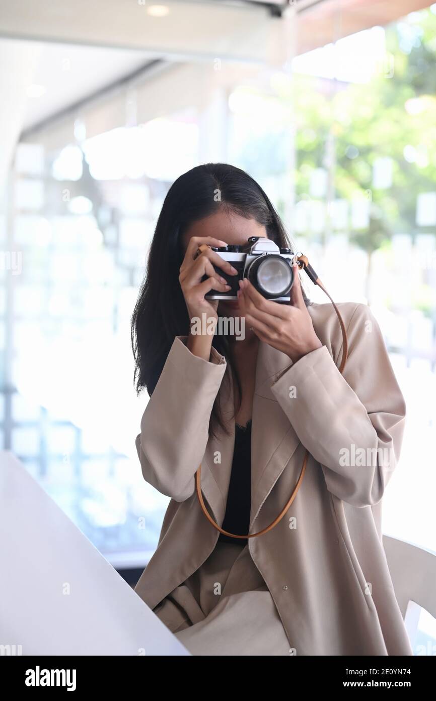 Portrait of young Asian woman taking photo with digital camera at her ...