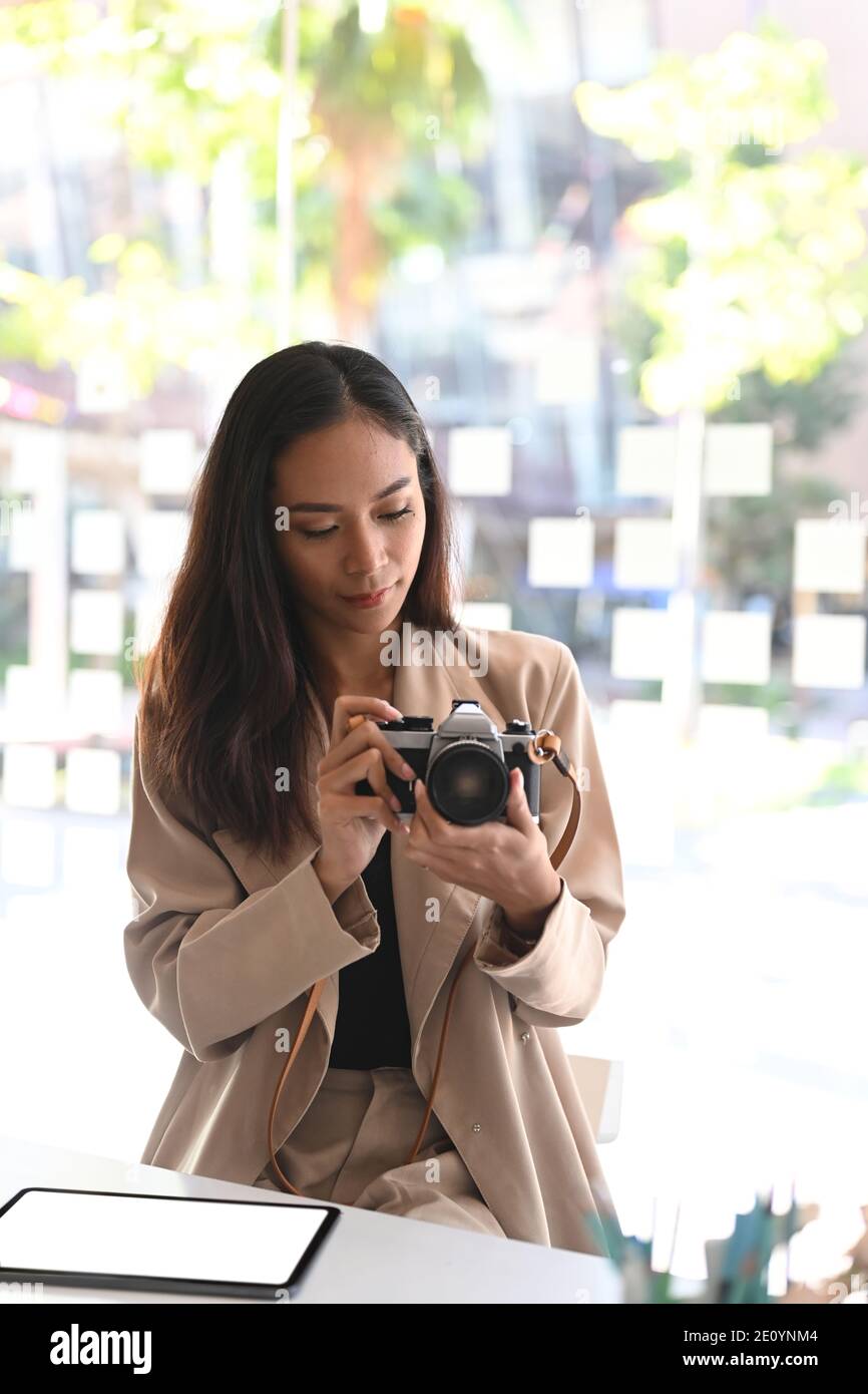 Portrait of beautiful woman photographer sitting at her work station ...