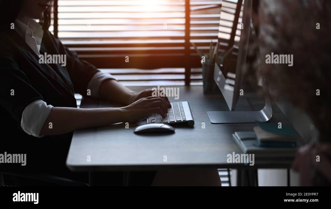 Side view of woman office worker working with computer and sitting by ...