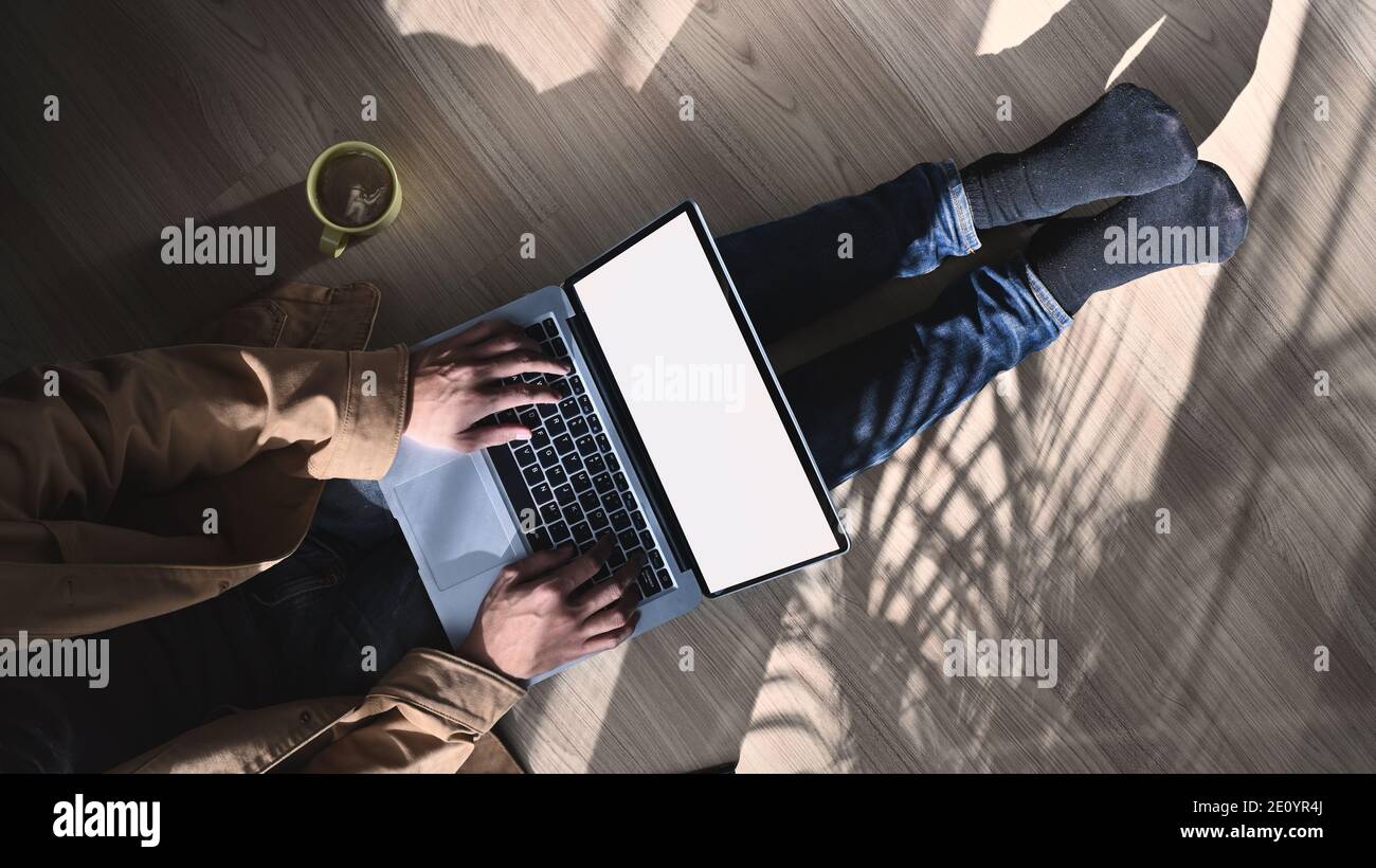 Over head shot of casual man freelancer sitting on floor and working on ...