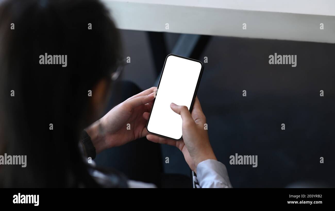 Rear view of young female using mock up mobile phone while sitting at ...