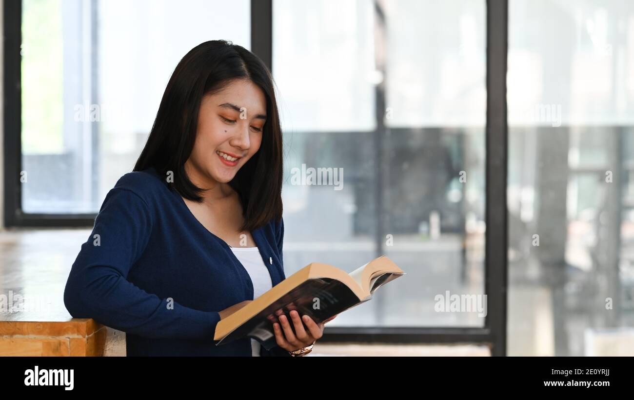 Image of young Asian student reading a book and sitting in the library ...