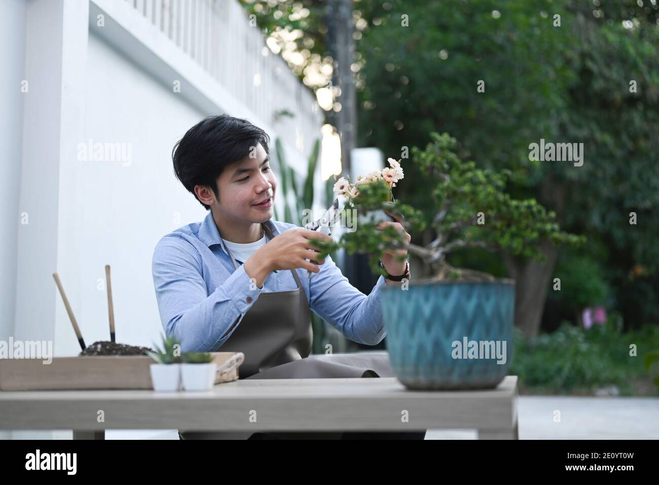 A cheerful gardener holding special scissors pruning flower at home ...