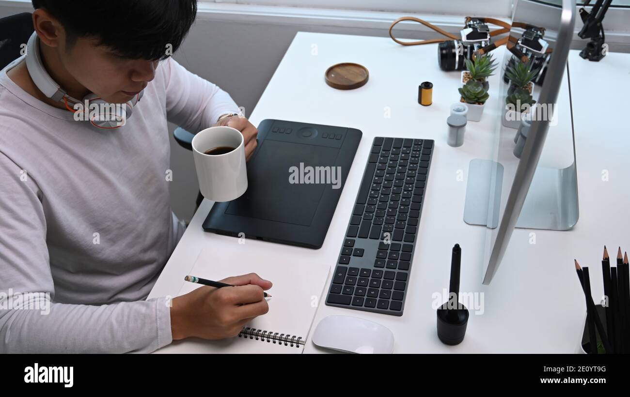 High angle view of young man photographer drinking coffee and making ...