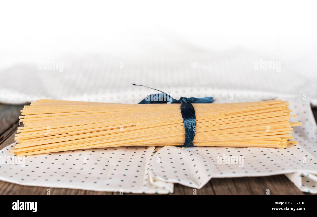 group of uncooked italian spaghetti pasta tied together by blue silk ...