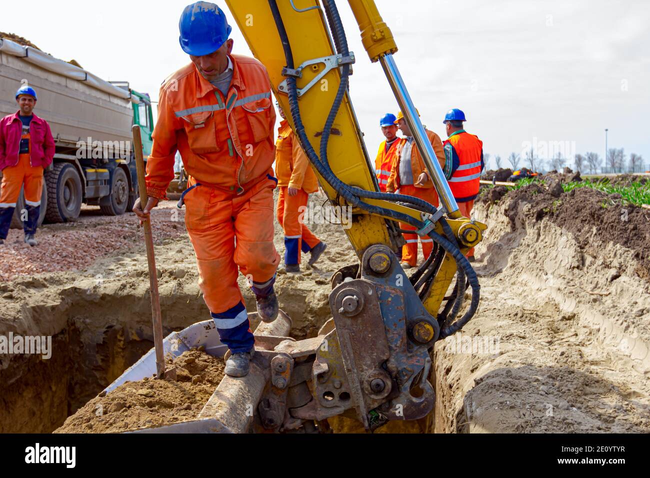 Worker is leap out from quadratic trench with little help of digger's ...