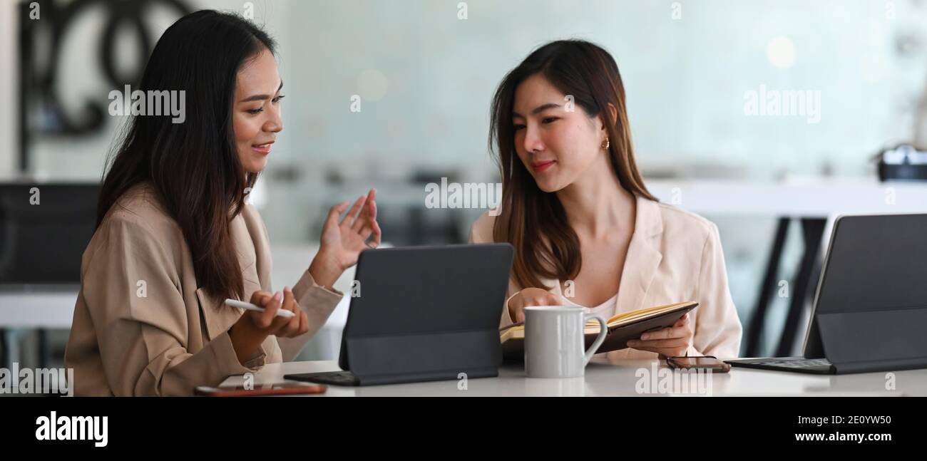 Happy colleagues sitting together at co working place and sharing ideas ...
