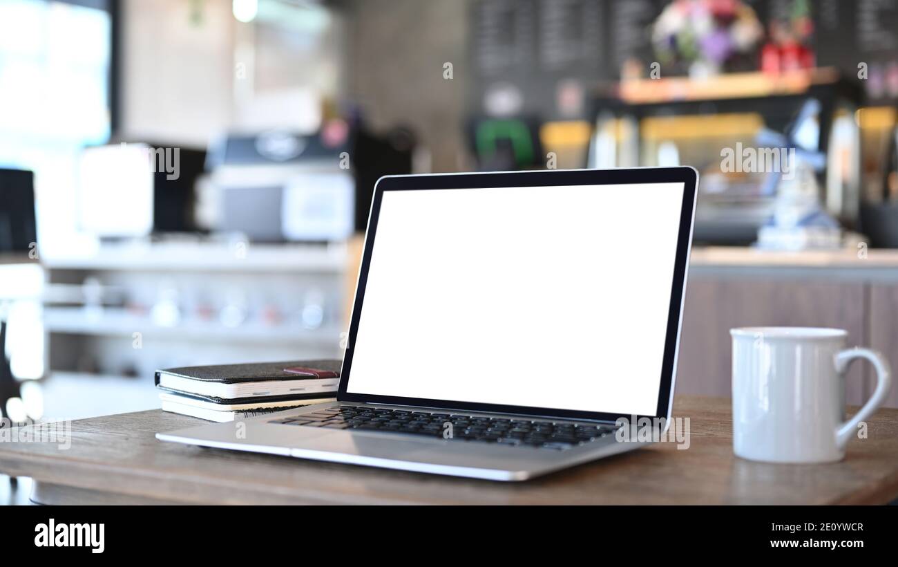 An open laptop computer with blank screen, coffee cup and notebook on ...