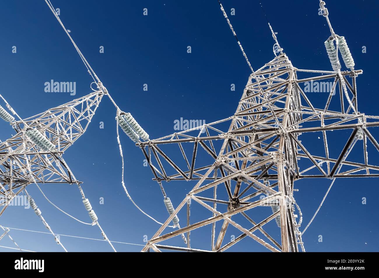 High-voltage wires and poles are covered with frost on a frosty winter ...