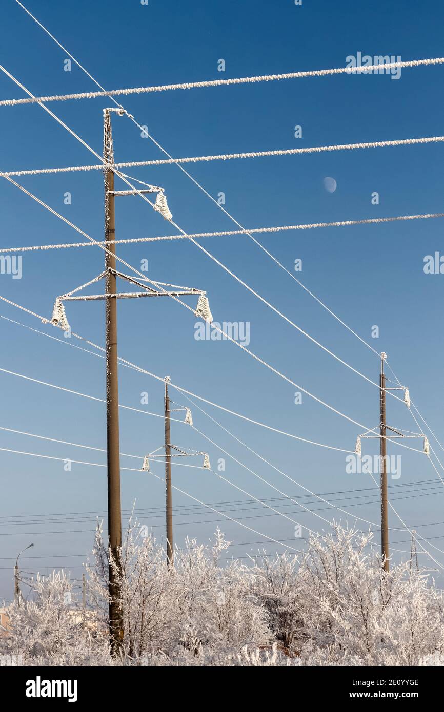 High-voltage wires and poles are covered with frost on a frosty winter ...