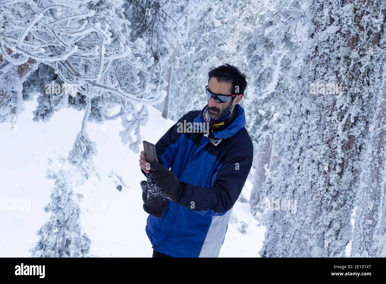 Man watch his smartphone in a snowy landscape. Communication concept in ...