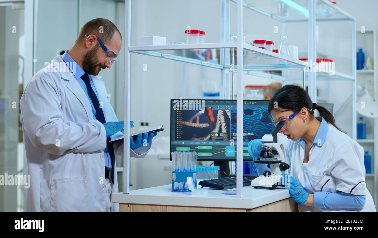 Team of scientists doing biological researches under microscope, lab ...