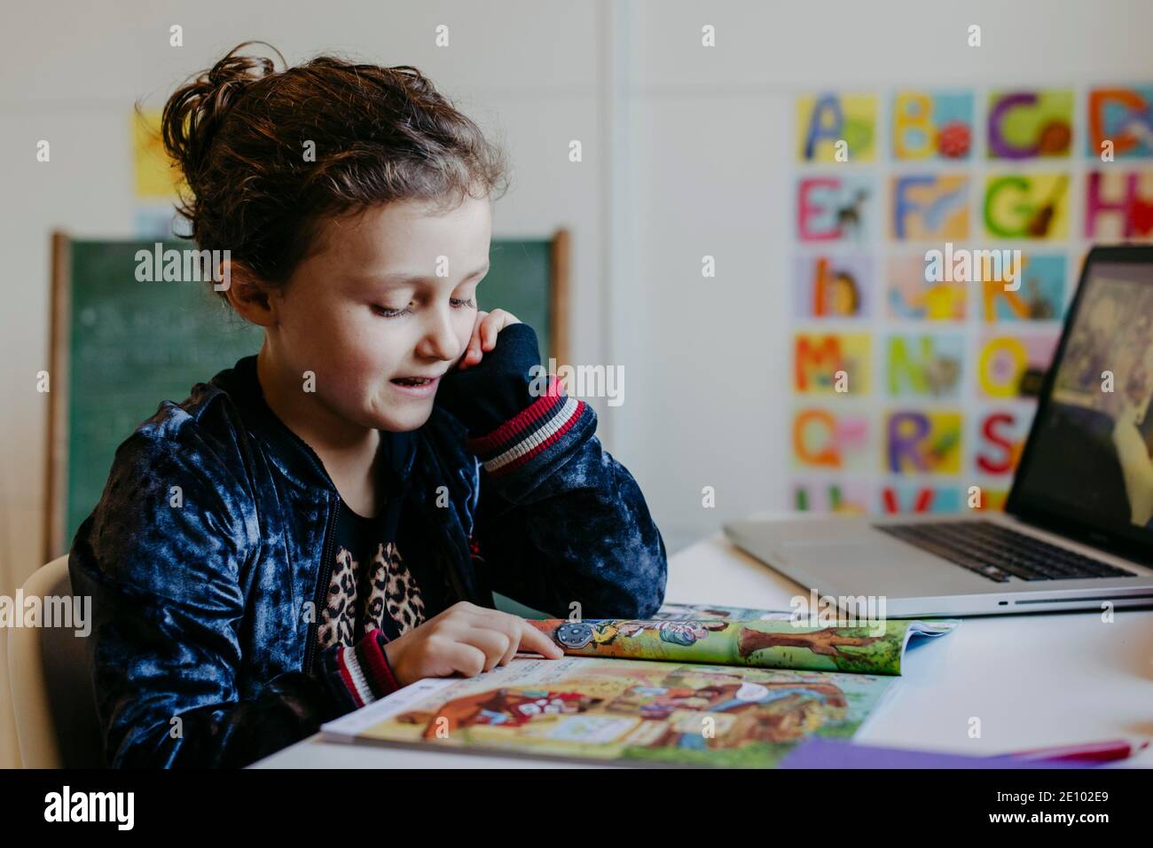 Little girl learning with reading book and laptop, homeschooling Stock ...