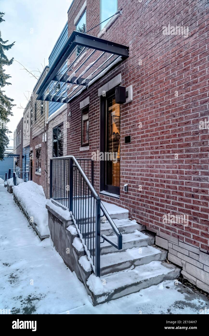 Brick building with stairs and glass entrance door viewed on a snowy ...