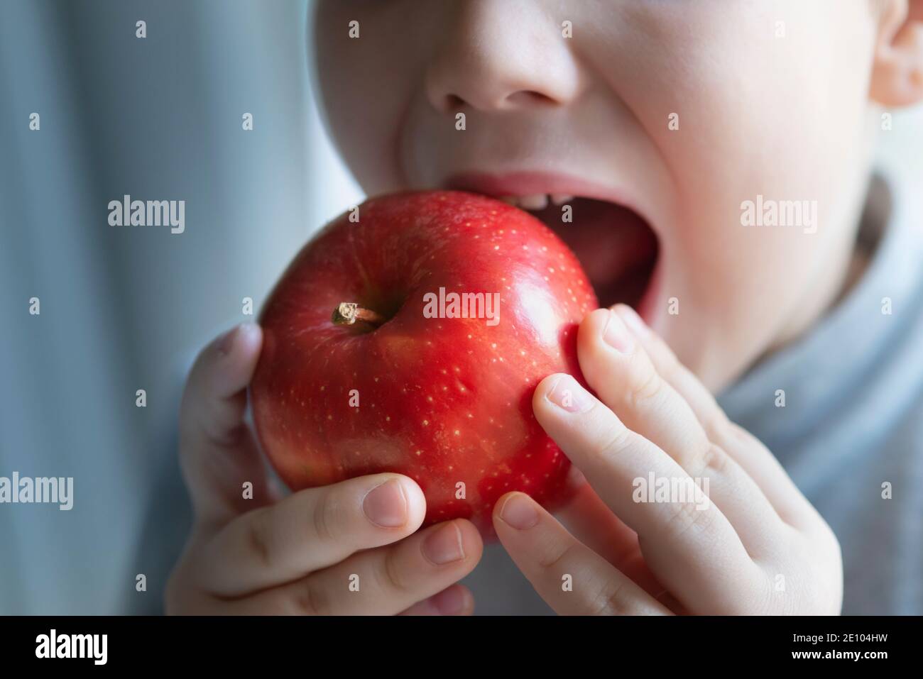 Boy Biting a Red Apple Stock Photo - Alamy