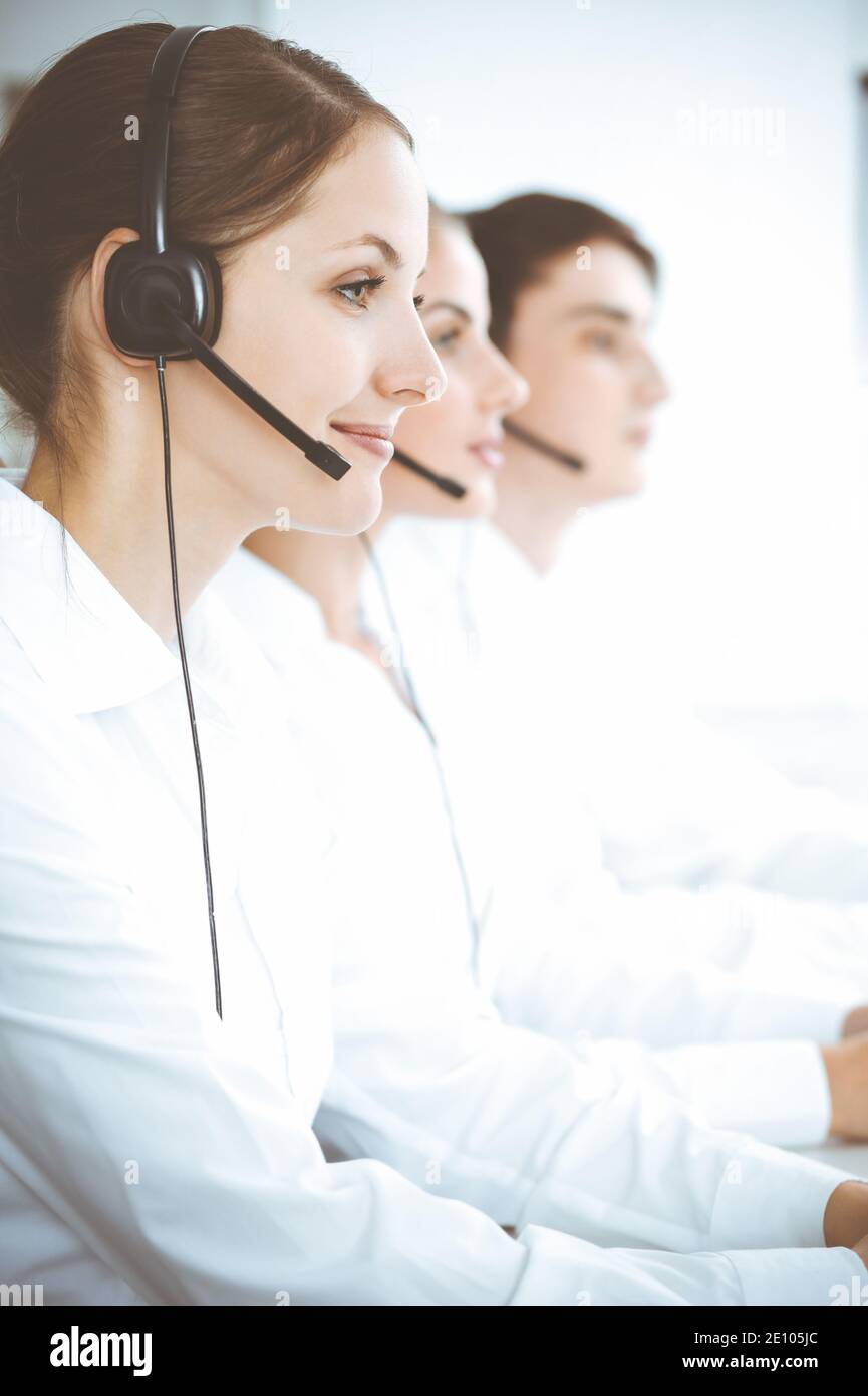 Call center. Beautiful young woman using headset and computer to help customers. Business ...