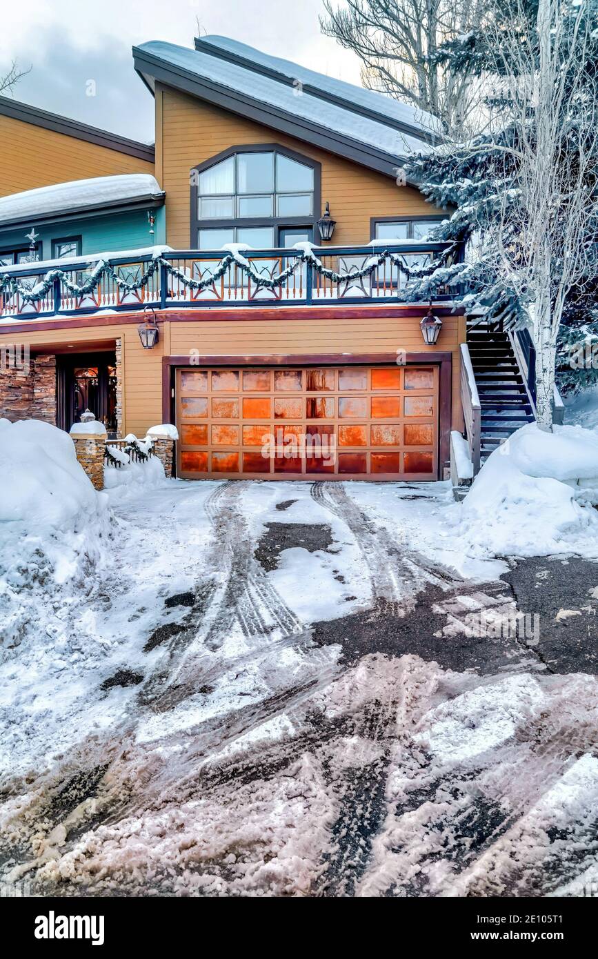 Tire tracks on snowy driveway leading to panelled metal garage door of ...