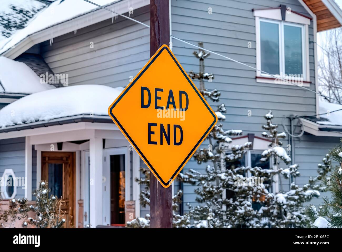 Bright dead end road sign on a post with gray home exterior in the ...