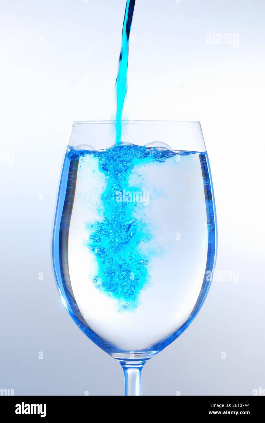 pouring blue liquid into clear water in glass Stock Photo - Alamy