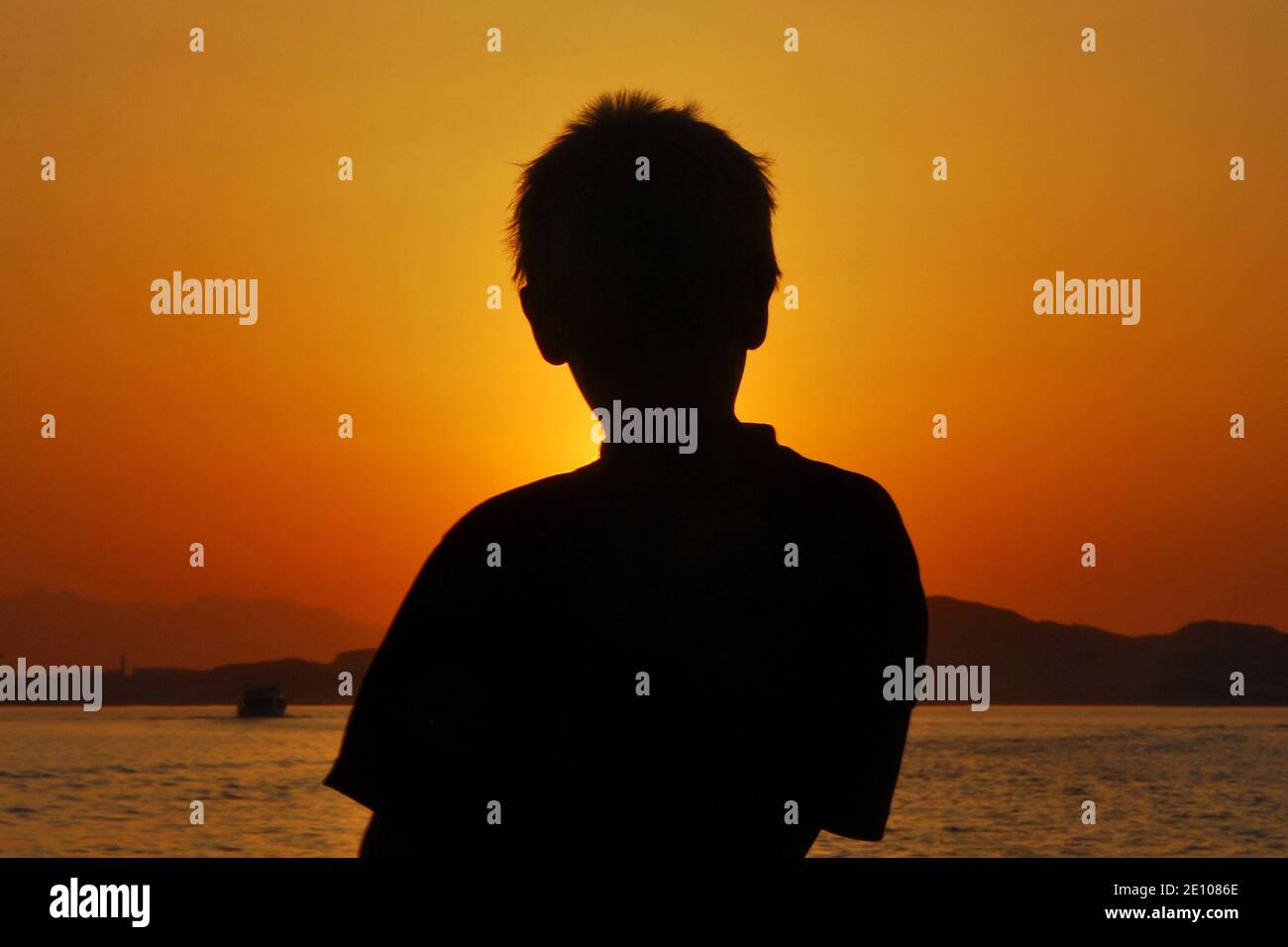 boy in the back light of sunset at sea Stock Photo - Alamy