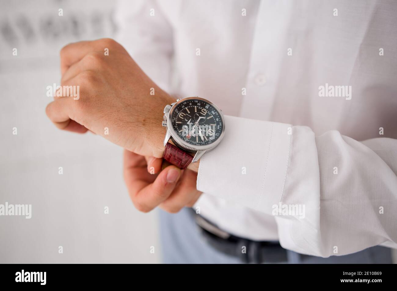 man puts a watch on his hand in a suit Stock Photo - Alamy