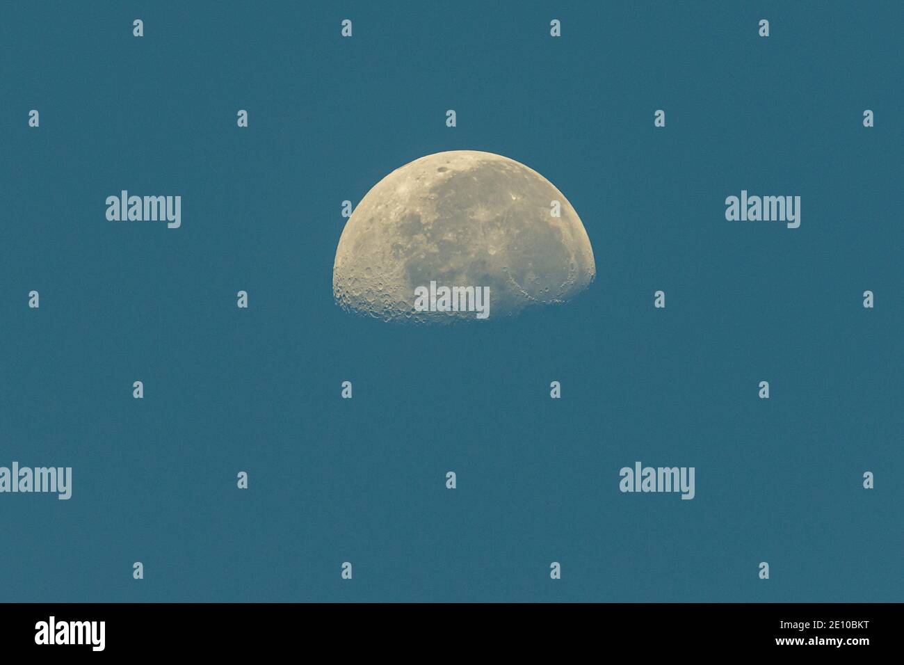 Moon on blue sky in the morning light with half moon setting and ...