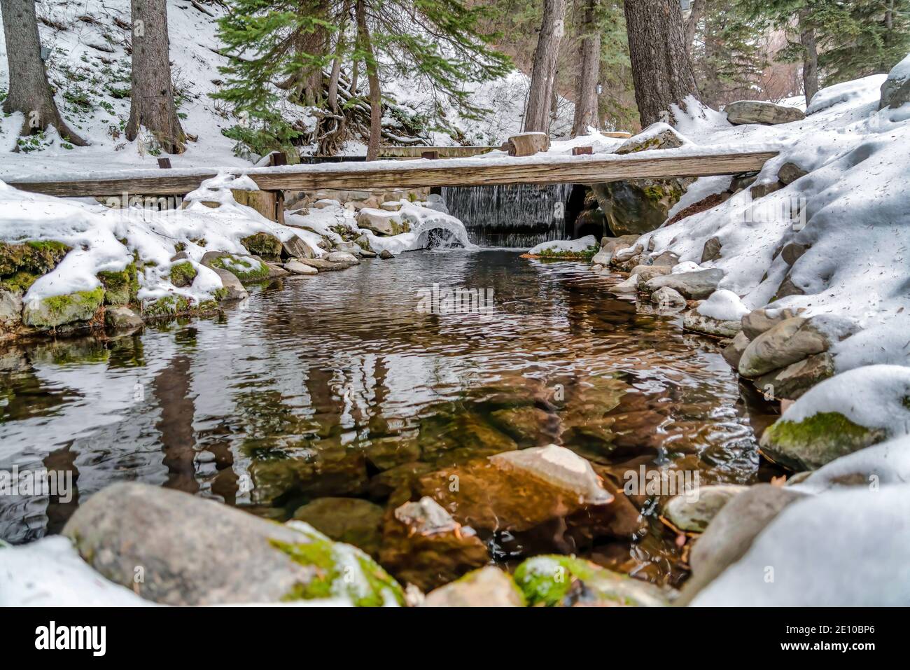 Clear stream water with huge rocks underneath surrounded by snowy ...