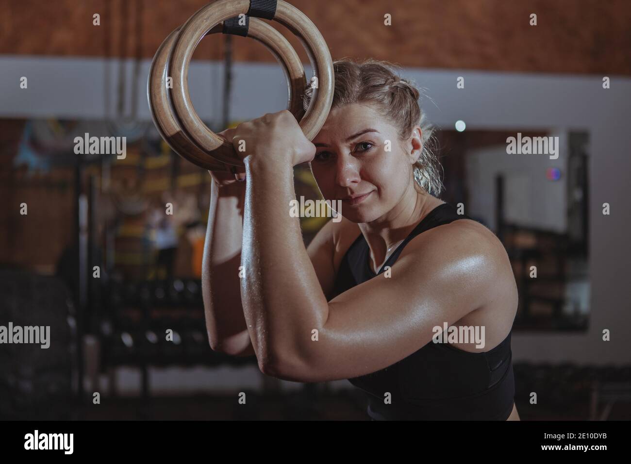 Charming female crossfit athlete smiling to the camera, holding ...