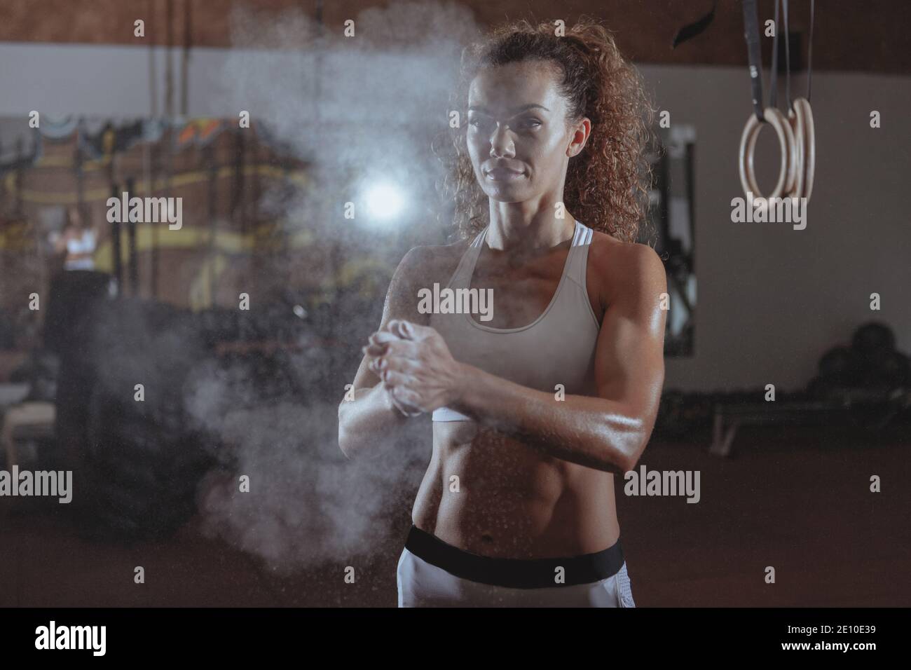 Attractive female crossfit athlete with muscular body chalking hands ...