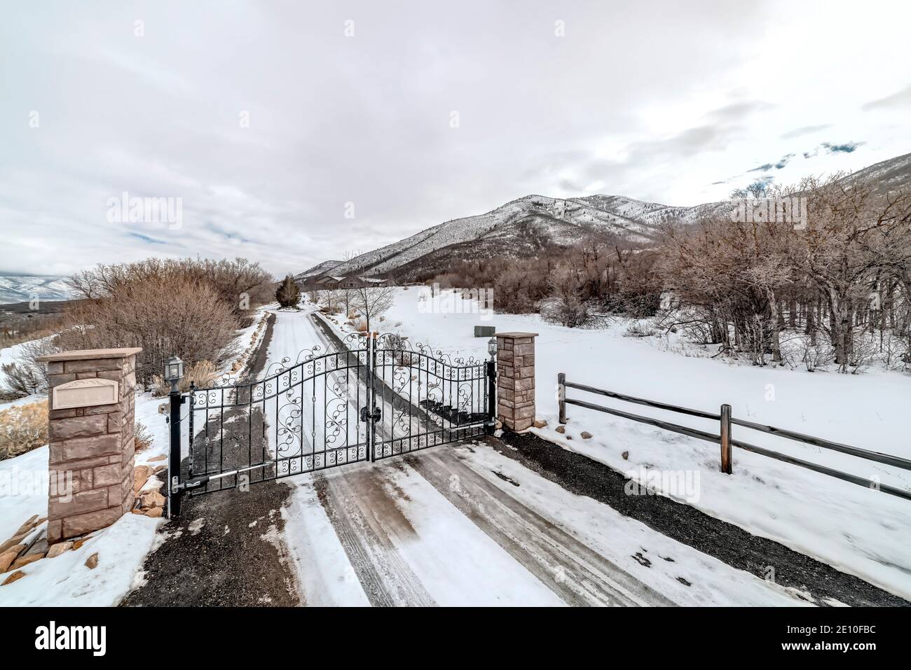 Road with iron gate in the mountain blanketed with snow on a cloudy ...