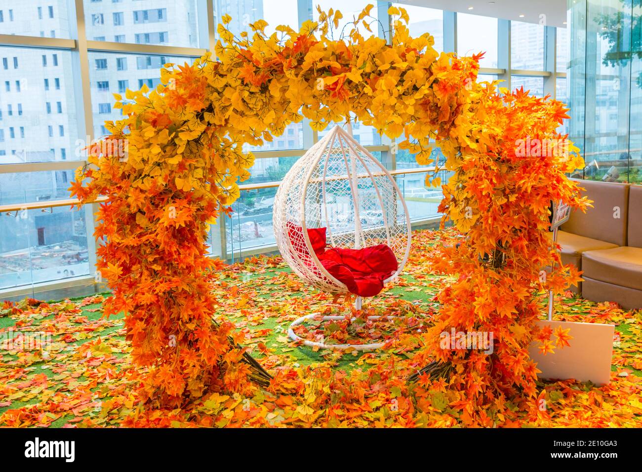 Arch with orange fall foliage with hanging white chair Stock Photo - Alamy