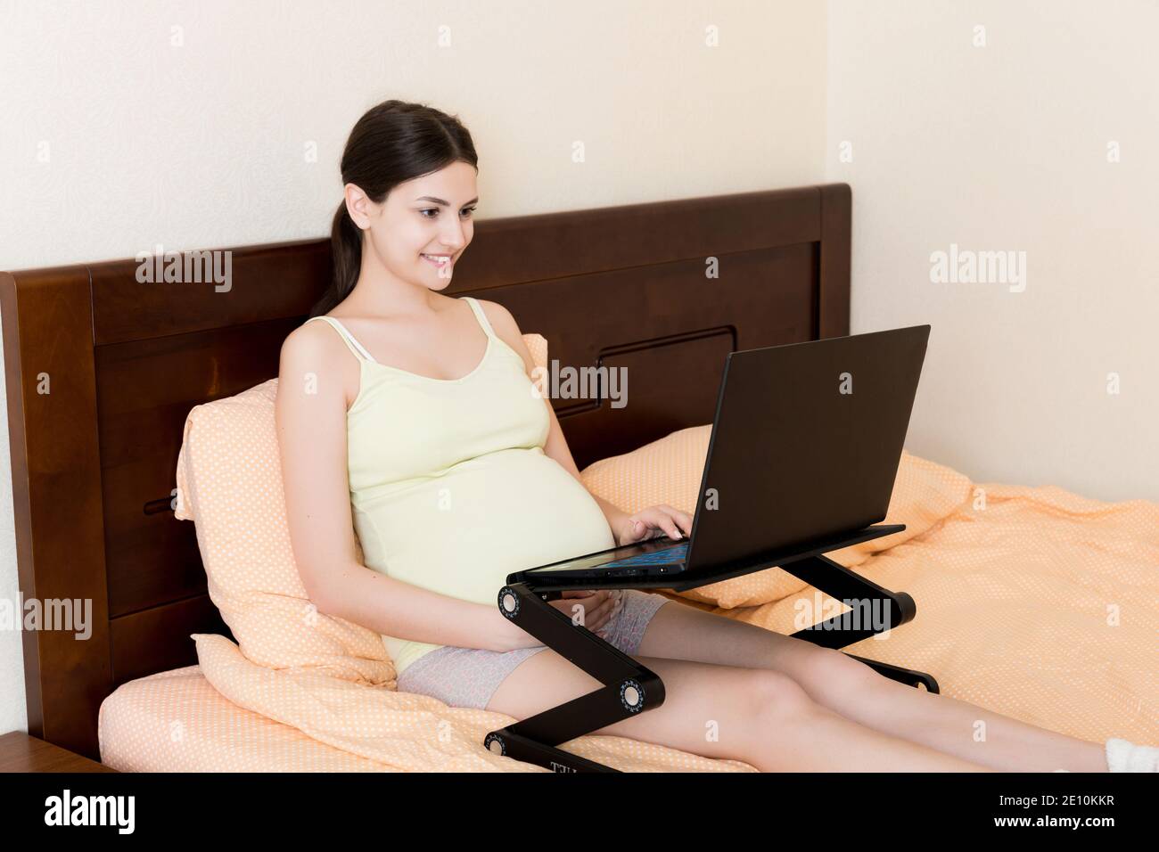 Pregnant Woman Using Laptop Computer in home on bed. Pregnant morning ...