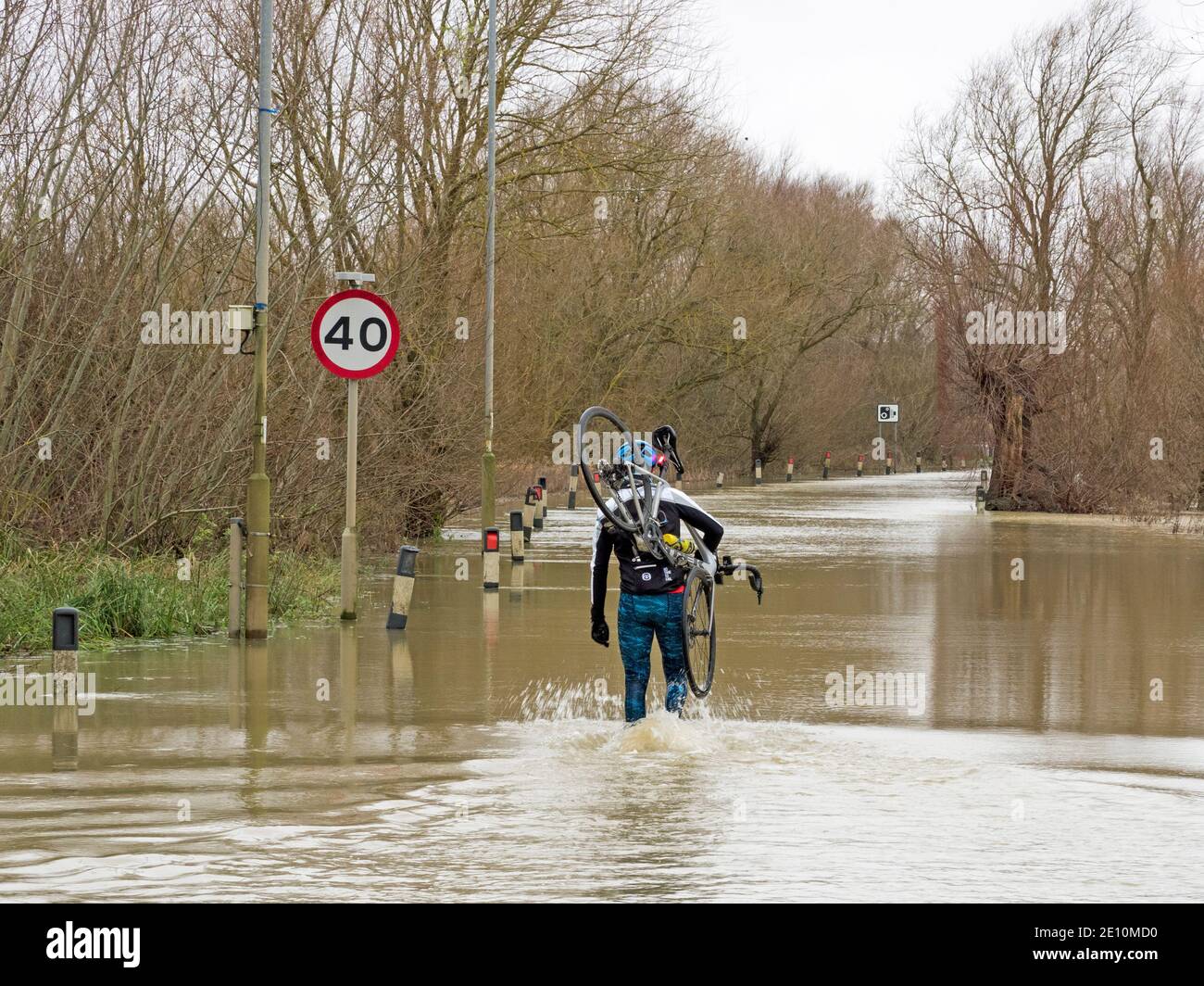Cyclist carrying bike along the flooded road (A1123 causeway) at Earith ...